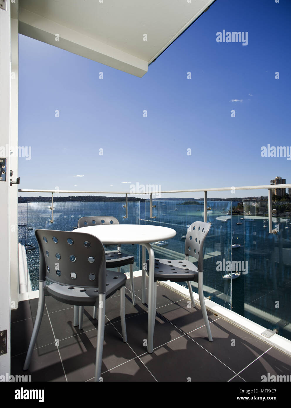 Table and chairs on paved balcony overlooking bay Stock Photo - Alamy