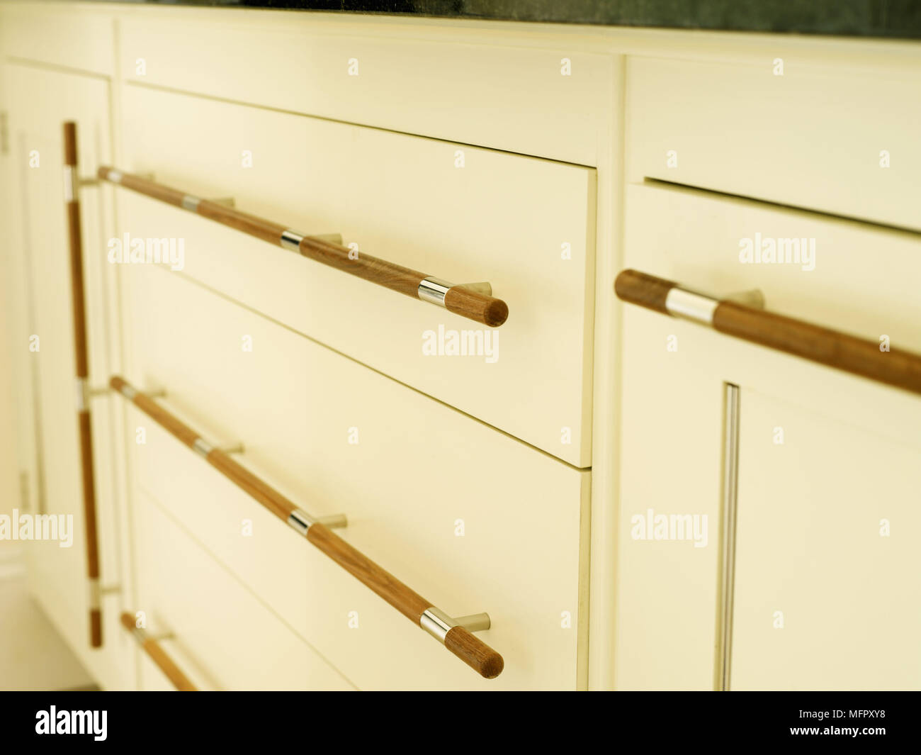 Wooden and steel handles on fitted kitchen units Stock Photo - Alamy