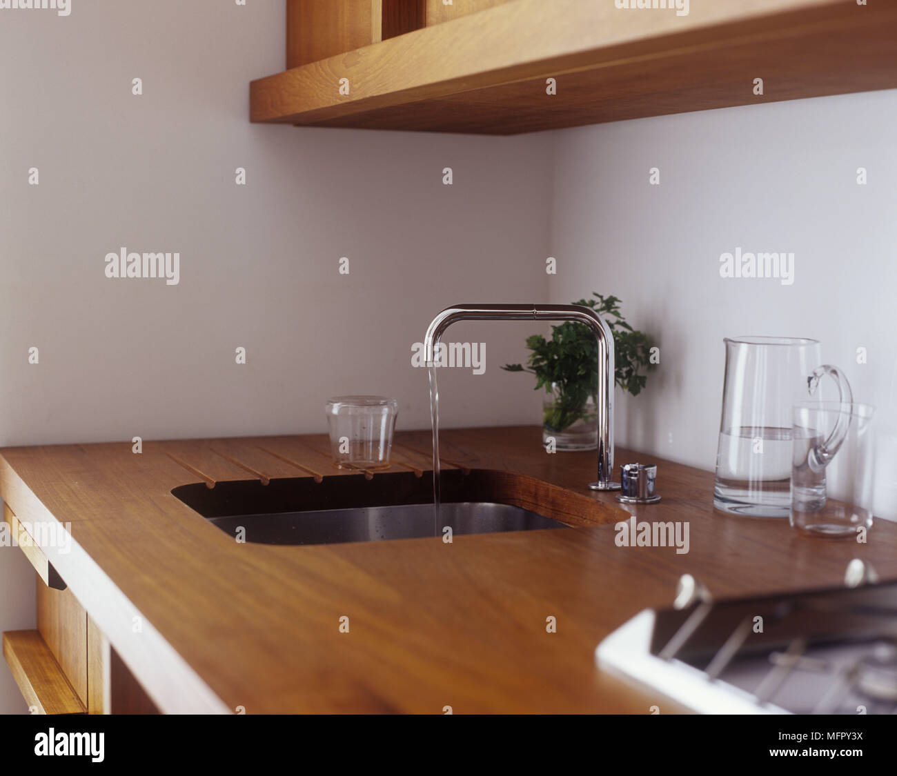 Water running into sink in modern kitchen with wood units Stock Photo ...