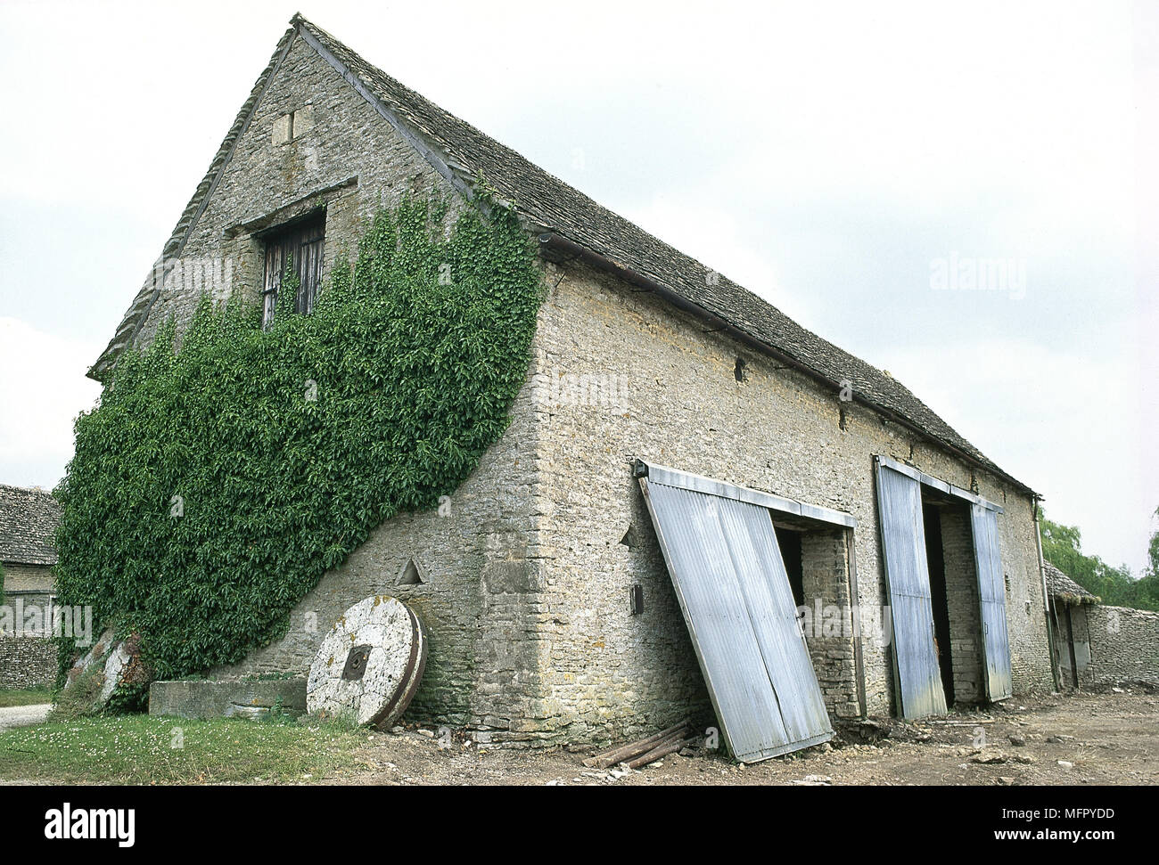 Exterior view of a rustic stone barn with vine-covered stone walls and ...