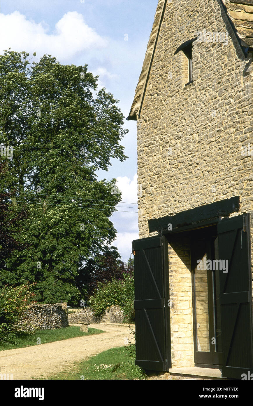 Exterior view of a converted stone barn with open, black painted double ...