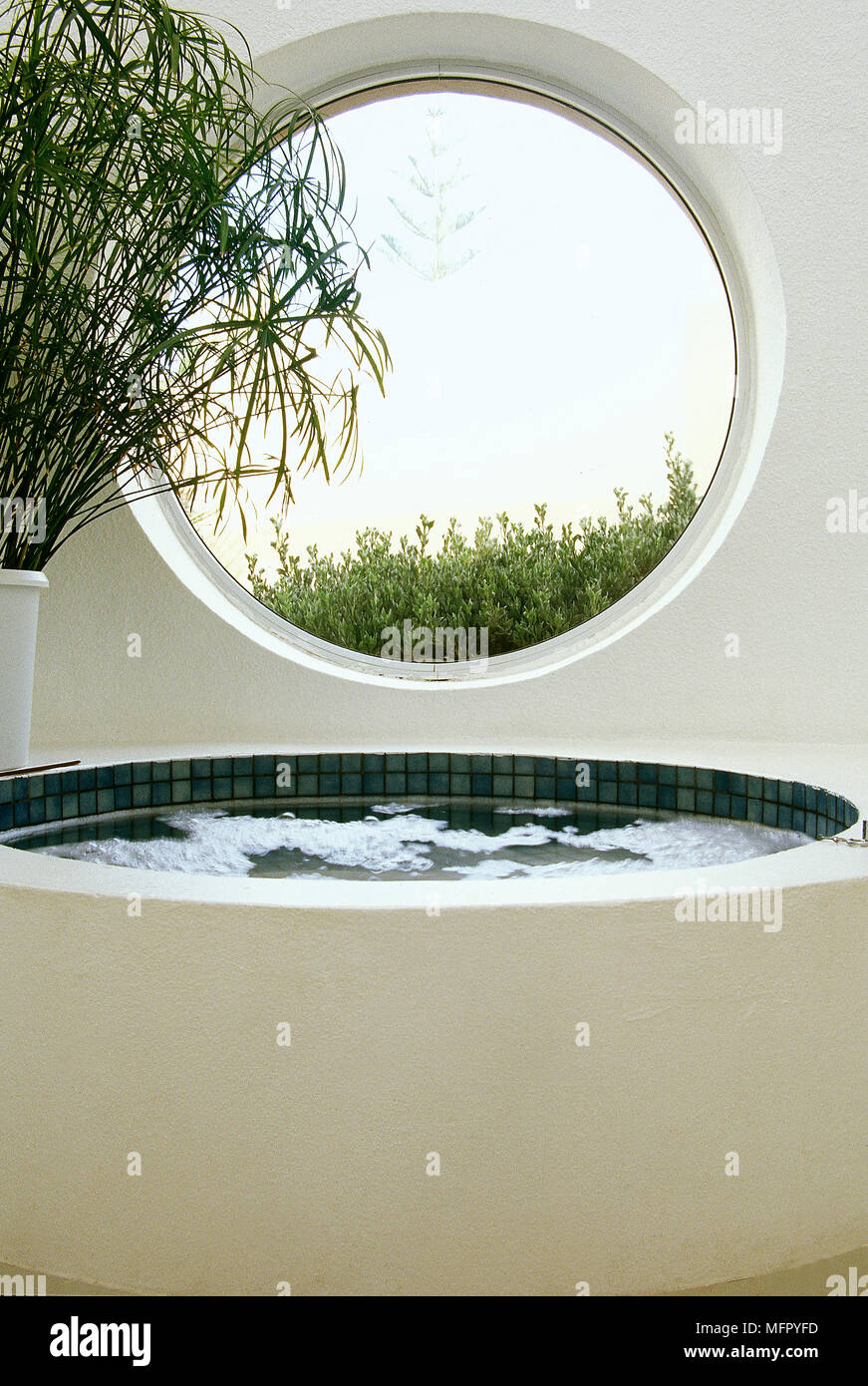 Modern bathroom detail with a filled, round bathtub, under a circular ...