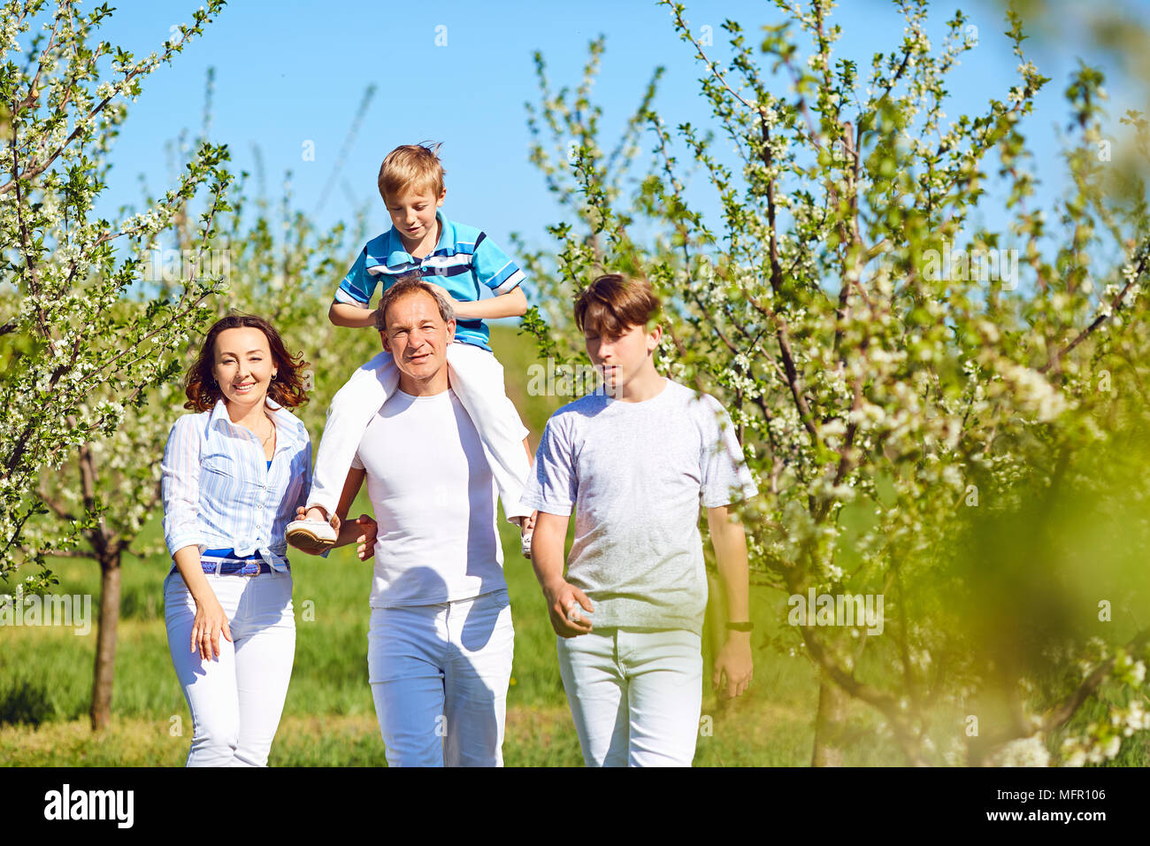A happy family walks in the garden in spring, in the summer Stock Photo ...
