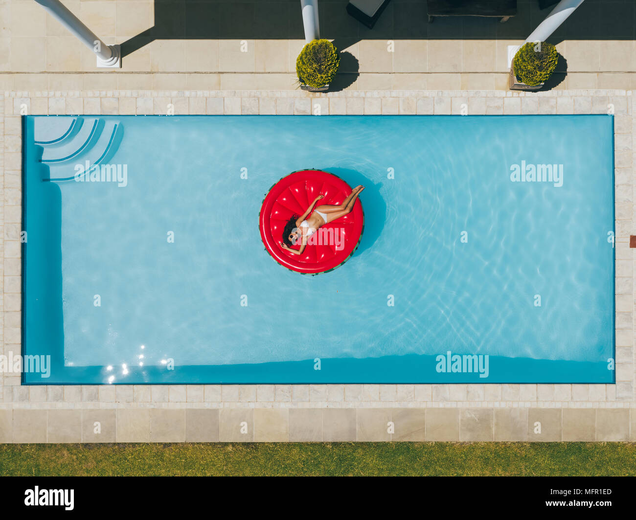 Aerial view of woman relaxing on a inflatable mattress in resort pool ...