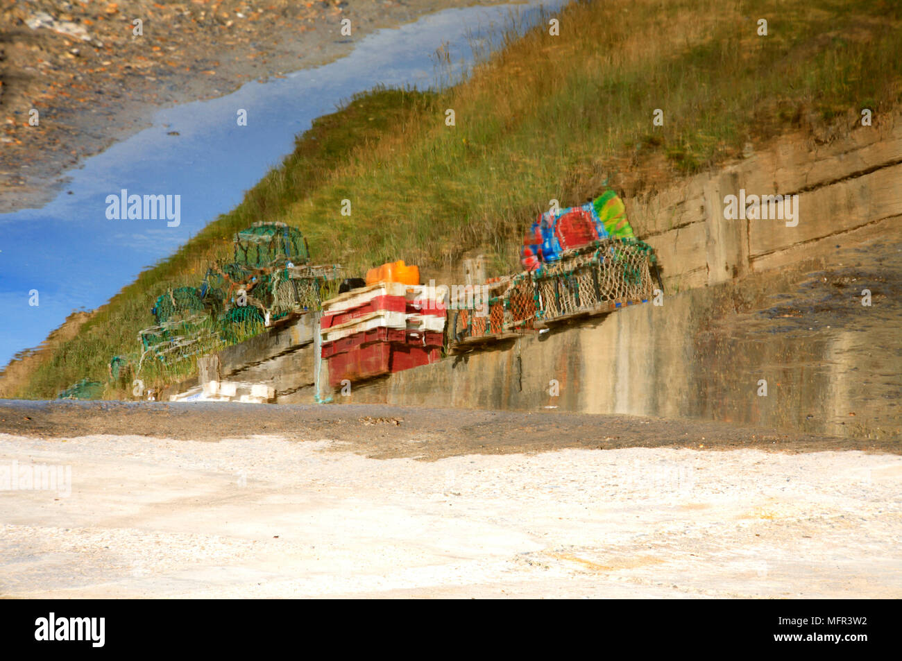A reflection of crab pots and fish boxes in a pool on the promenade at ...