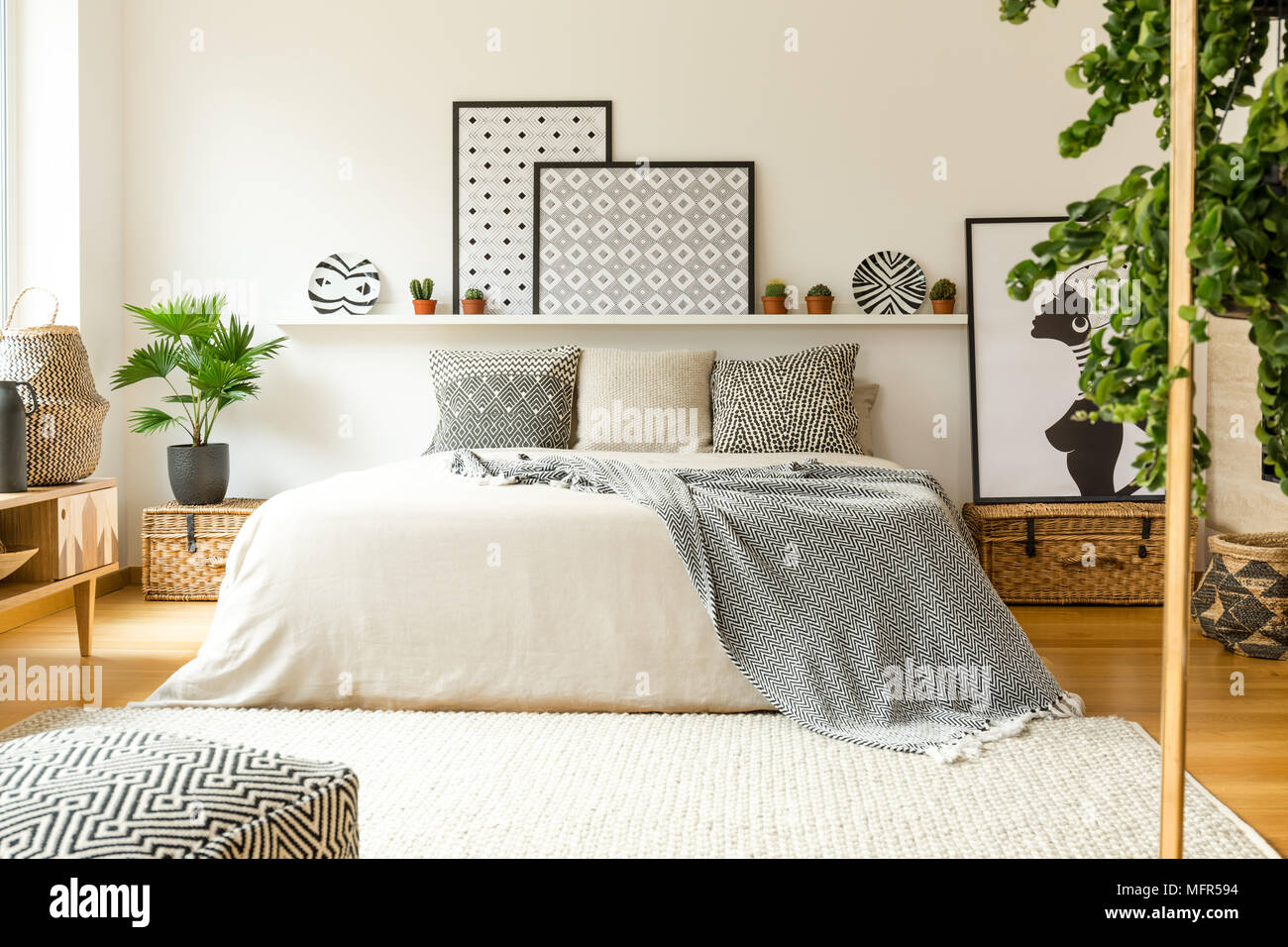 Warm bedroom interior with a comfy bed, patterned blanket and pillows ...