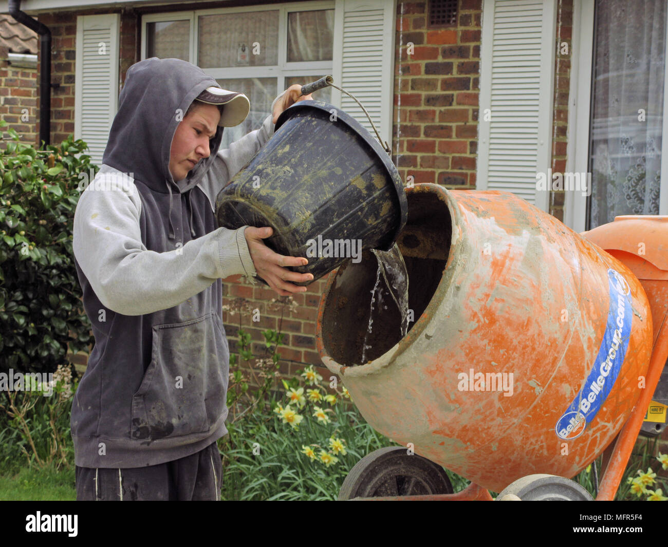 Apprentice builder mixing up cement in a cement mixer model release ...