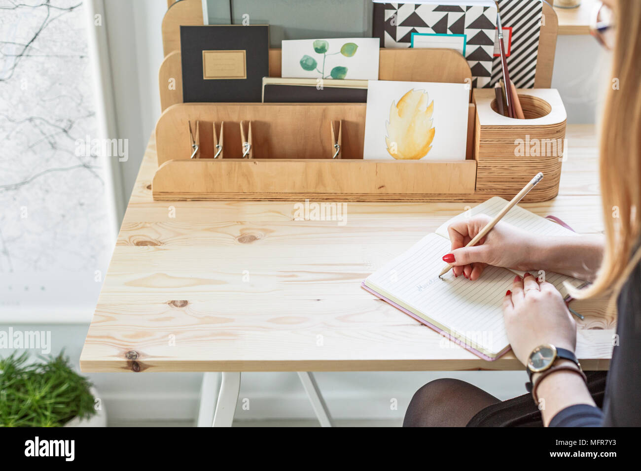 Close up of a girl writing a diary with a pencil sitting at a wooden ...