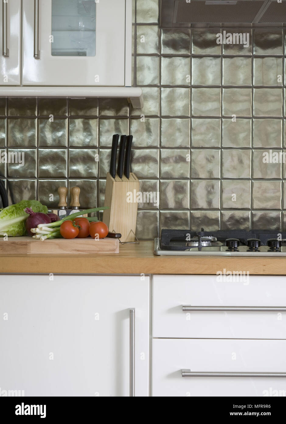 Food on chopping board on worktop next to gas hob set in modern kitchen ...