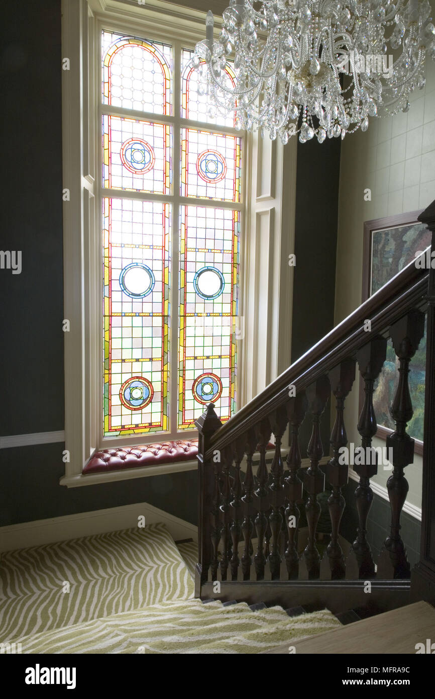Traditional style staircase leading down to window with stained glass ...