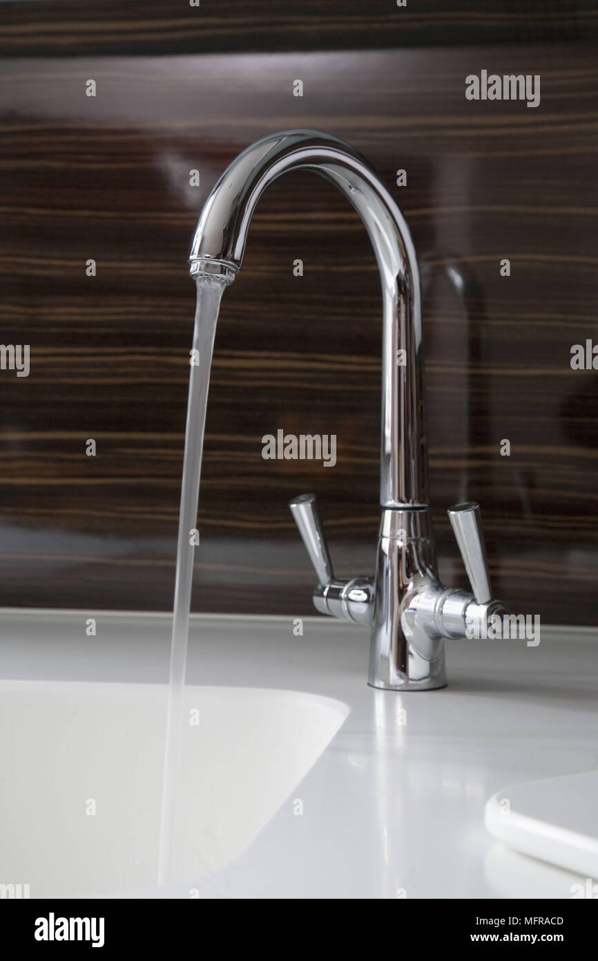 Water running from contemporary tap fitting into kitchen sink Stock ...