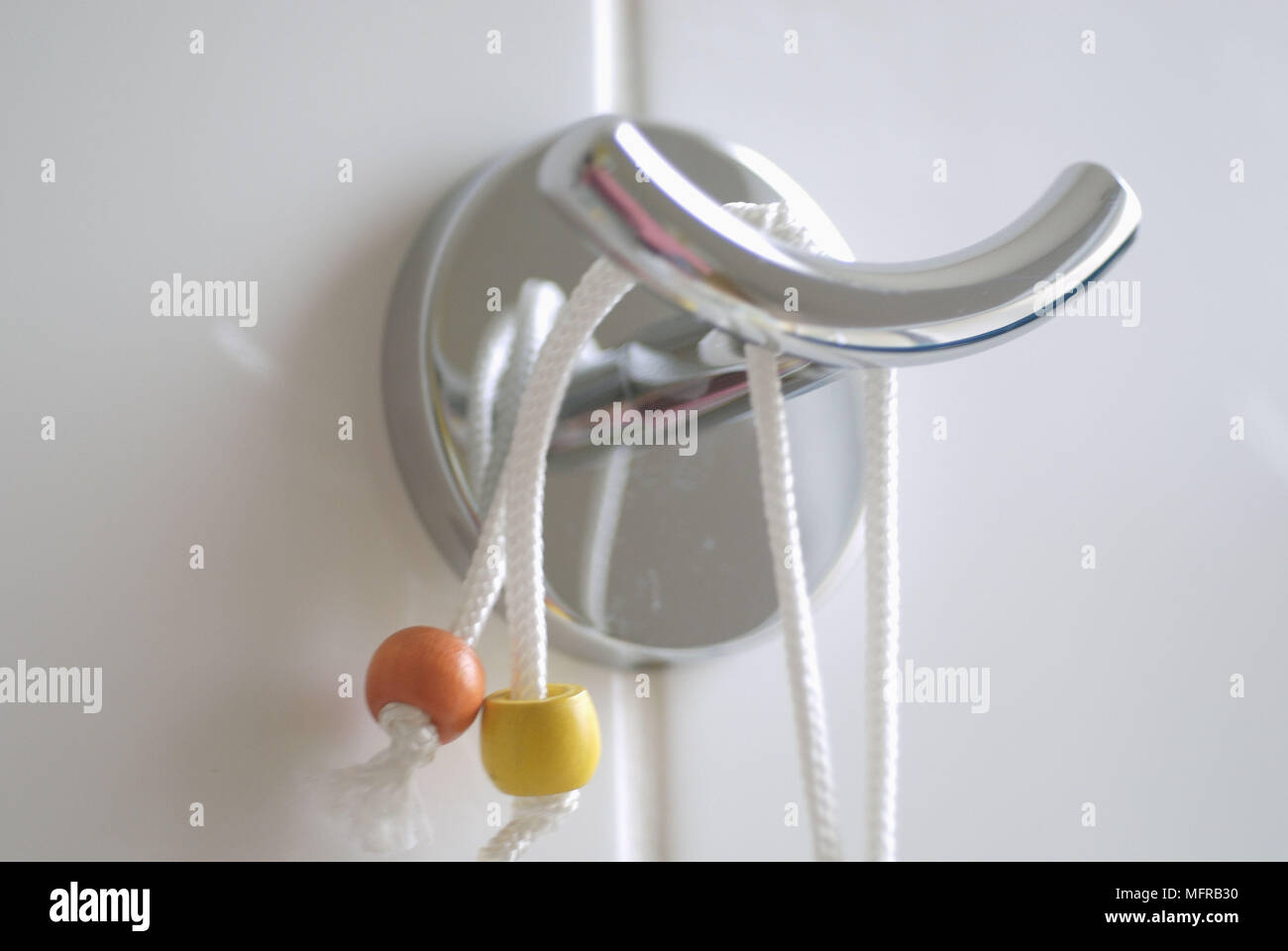 String and beads hanging from chrome hook Stock Photo - Alamy