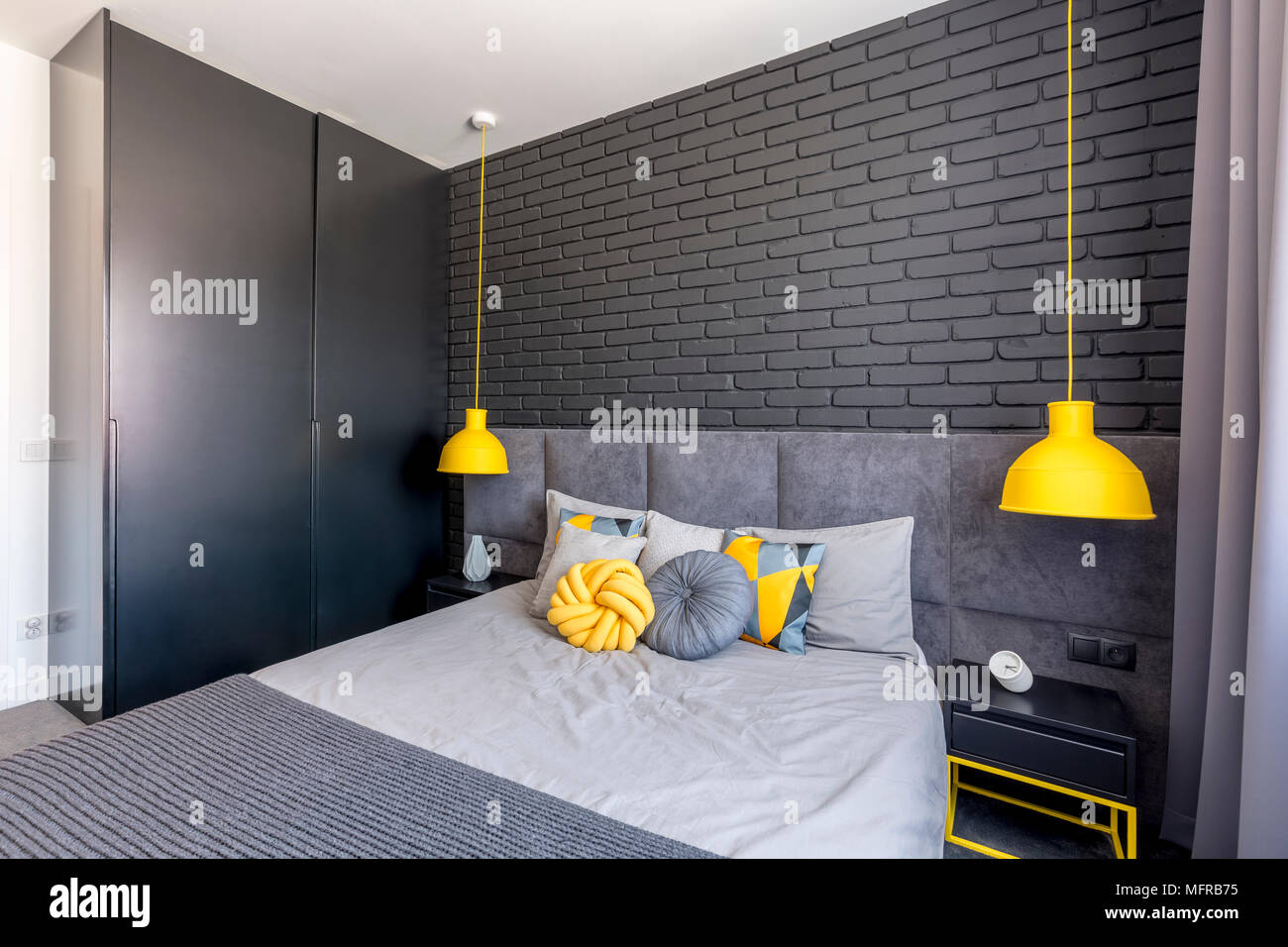 Large wardrobe, brick wall and gray bedding on the bed in elegant ...