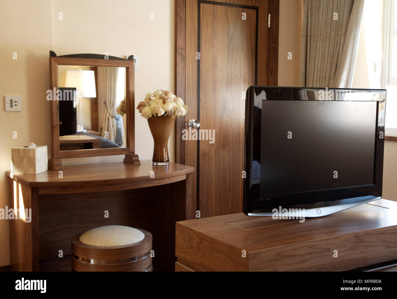Flat screen television on table in front of wooden dressing table Stock ...