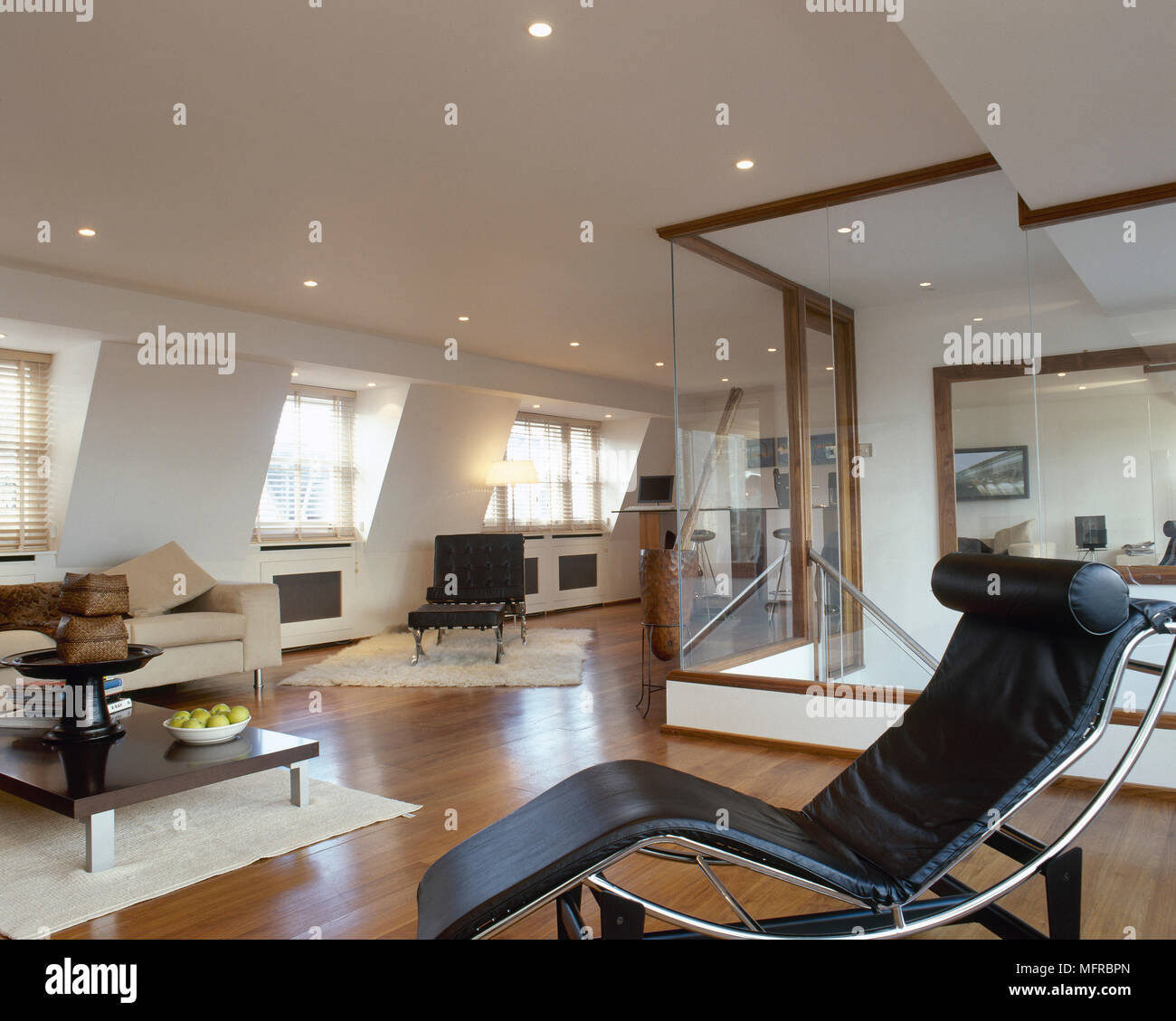 Open plan sitting room with wood floor, black leather recliner, glass ...