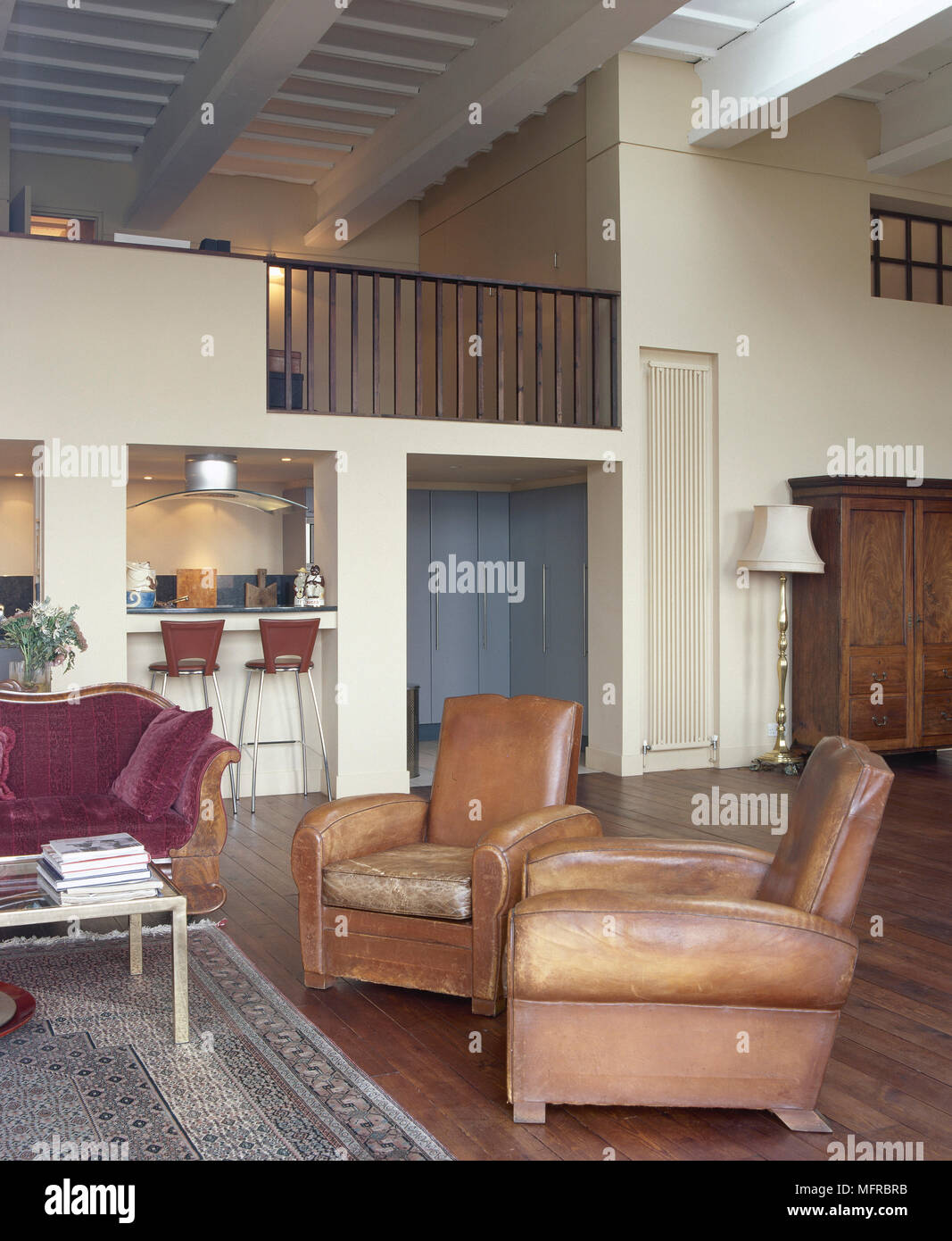 Spacious, open plan seating area with wood floor, leather armchairs ...