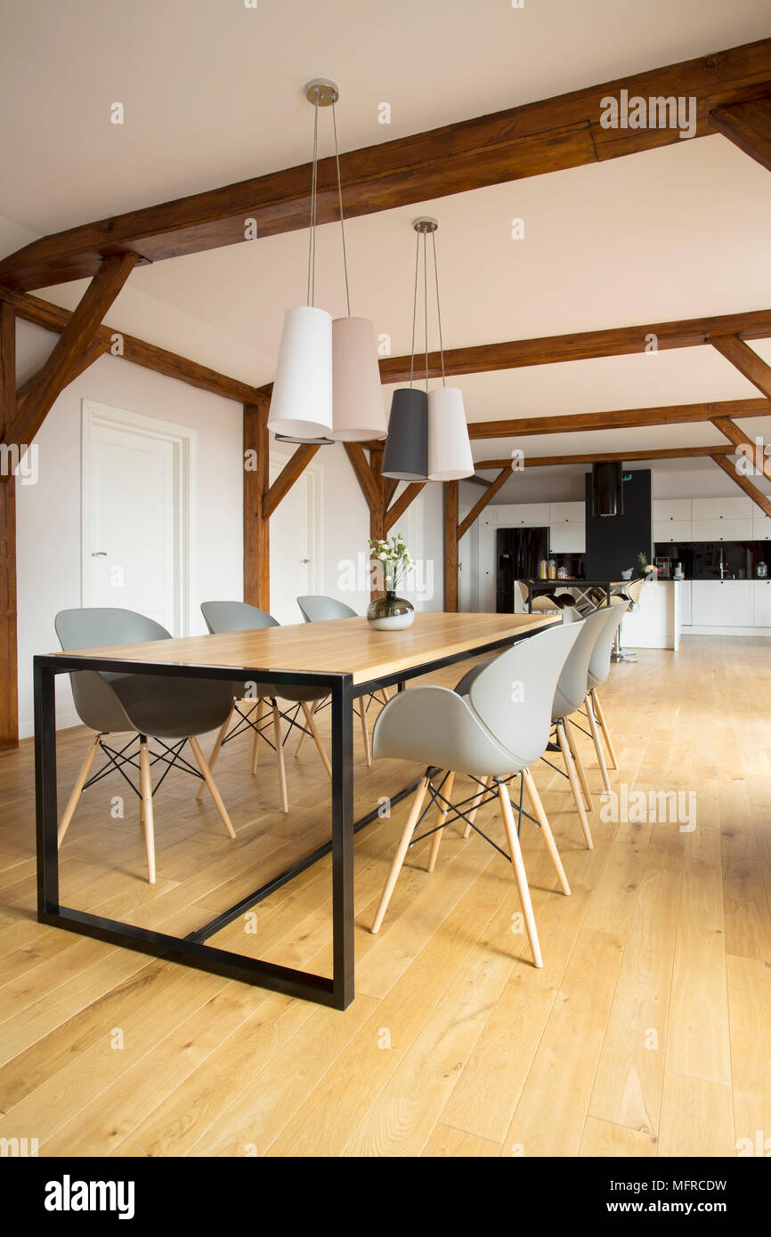 Side angle of wooden dining table with grey chairs set in spacious room ...