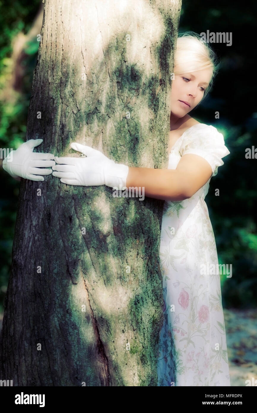 a woman in a floral dress is hugging a tree Stock Photo - Alamy