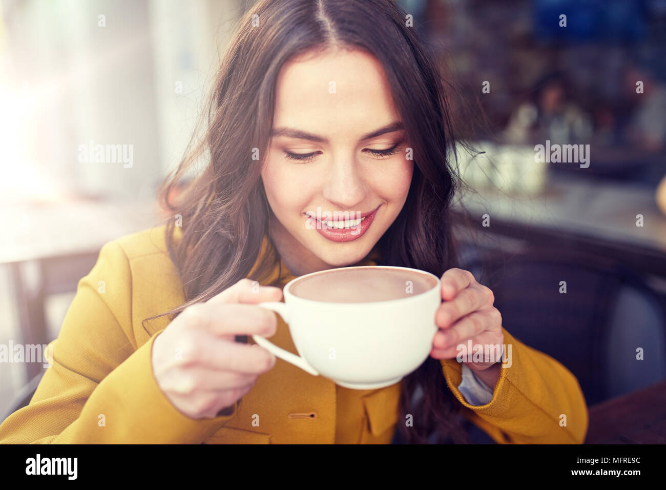 happy woman drinking cocoa at city street cafe Stock Photo - Alamy