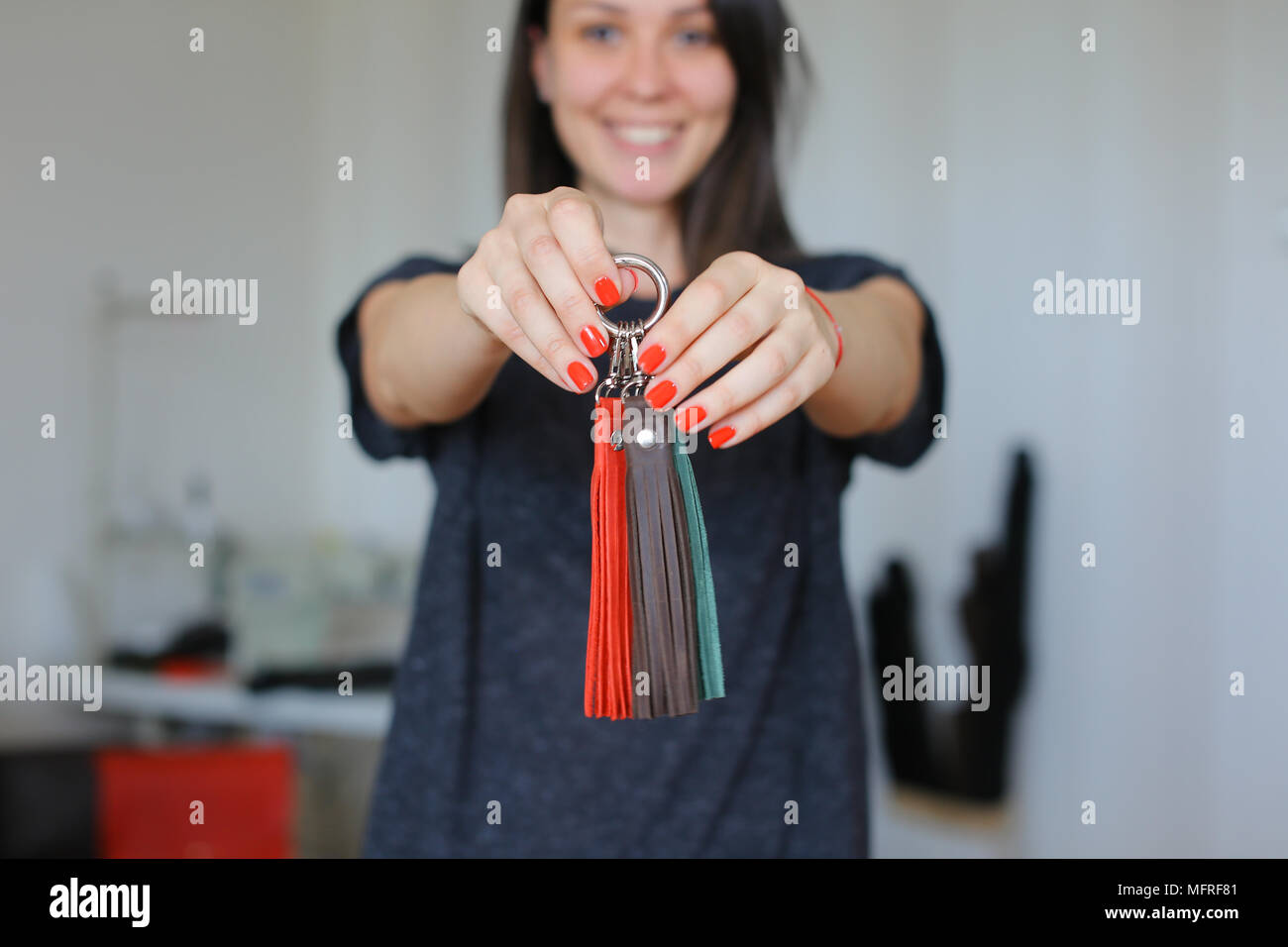 Happy female person standing with leather handmade trinkets at home ...