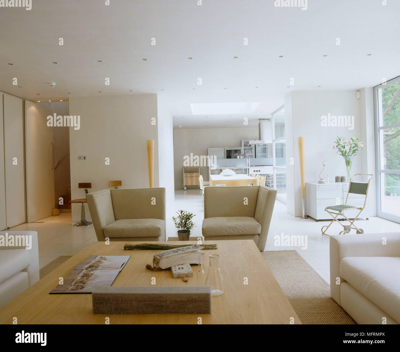 A modern neutral open plan sitting room with upholstered armchairs wood ...