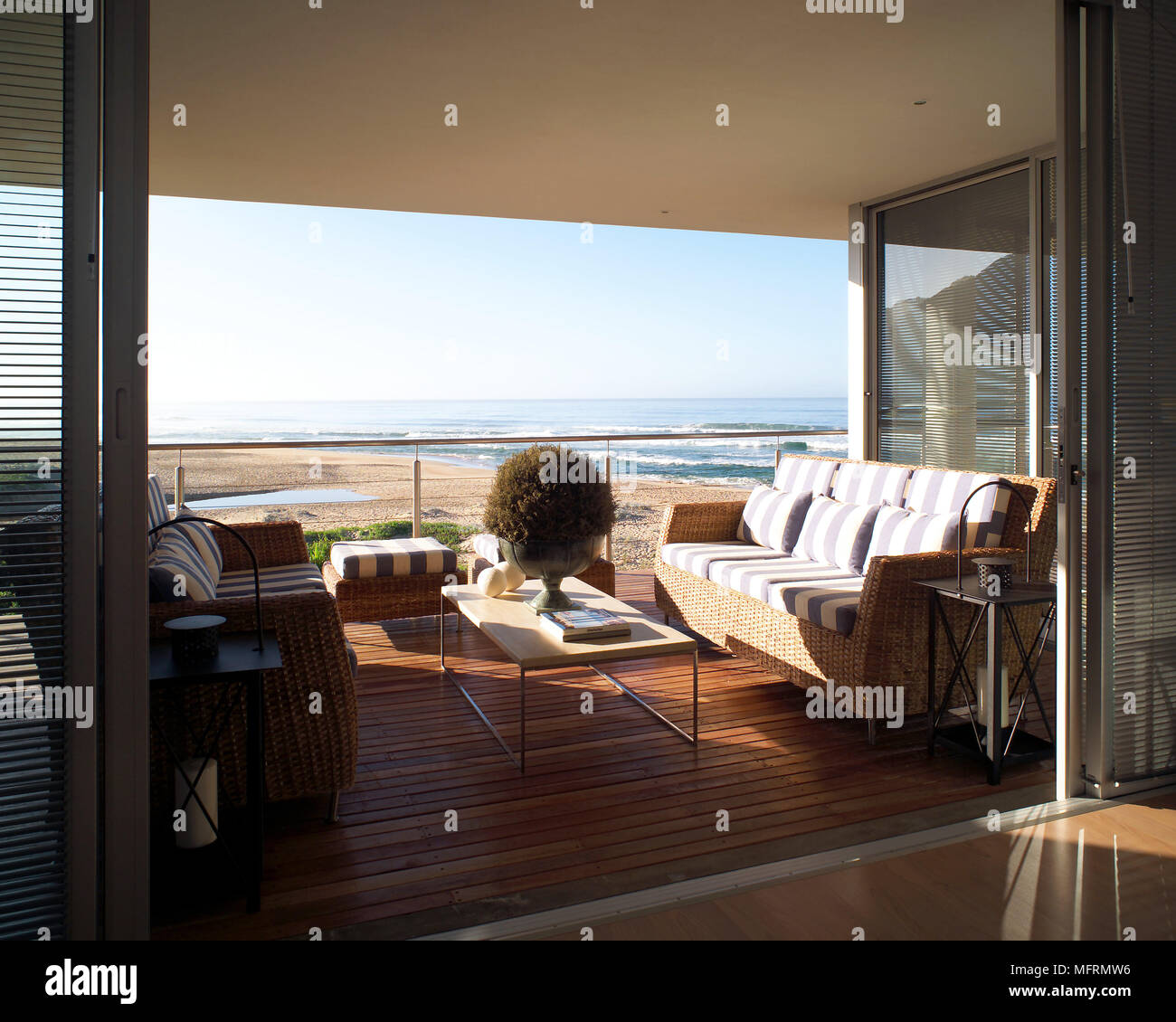 A modern covered terrace with decked patio area wicker seating stools ...