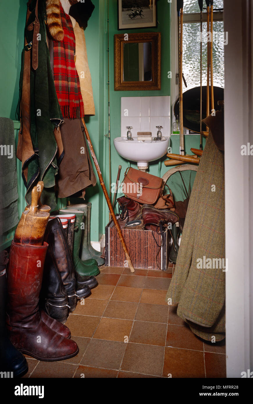 Collection of boots and country clothing in cloakroom with washbasin ...