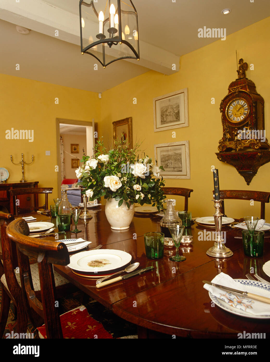 Wooden dining table with table setting in yellow room Stock Photo - Alamy