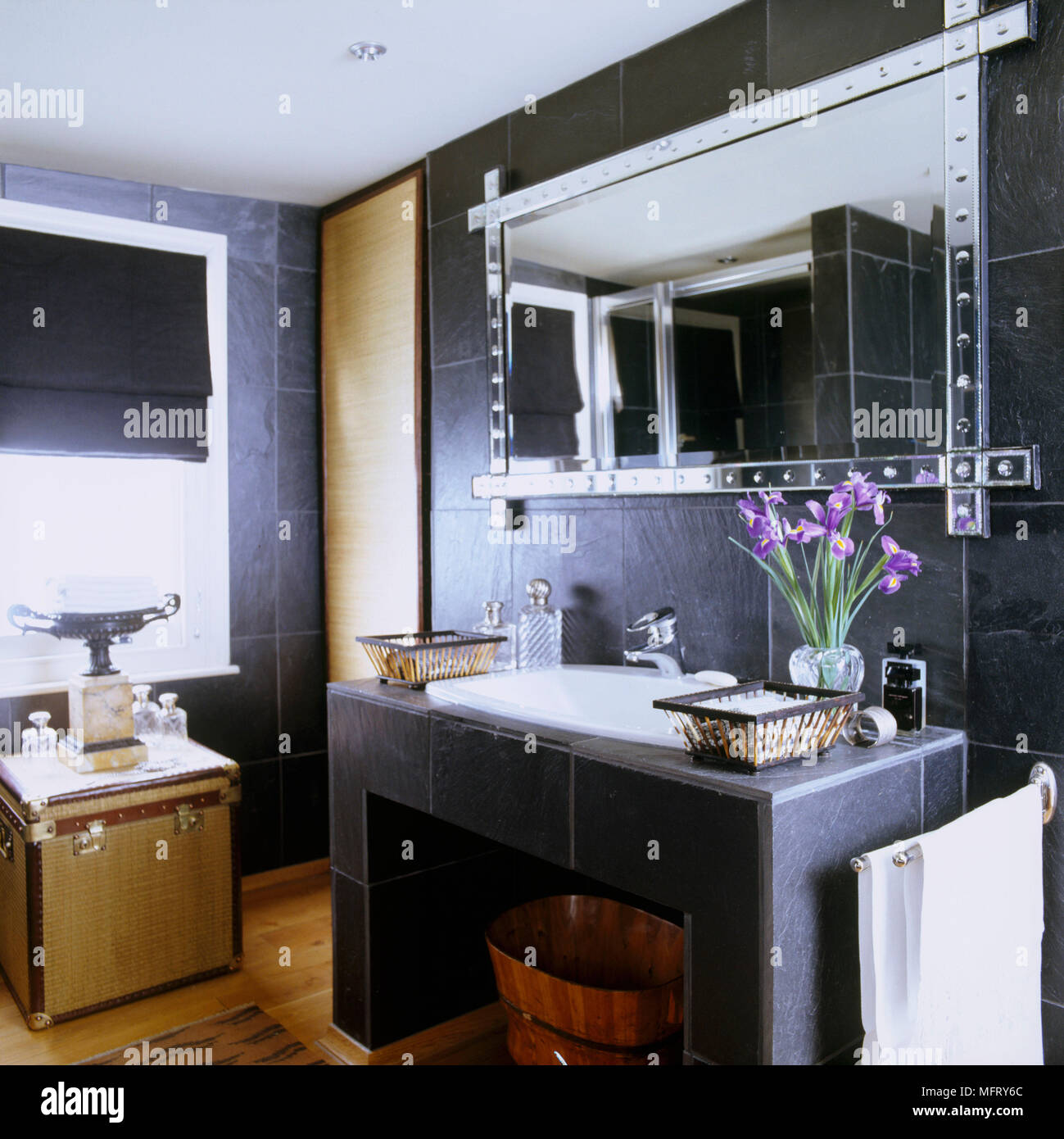 A detail of a modern tiled bathroom wash basin set in tiled surround ...