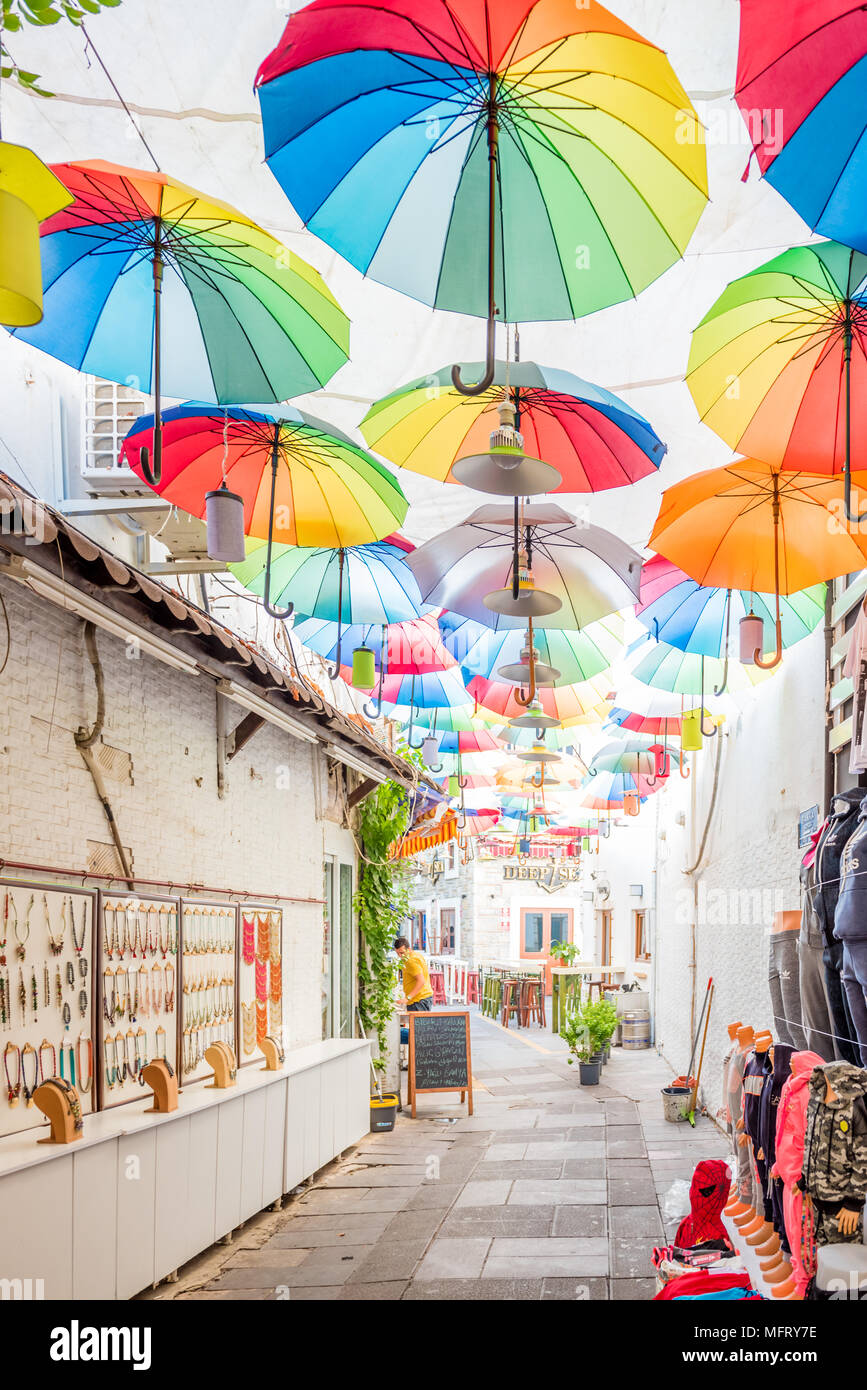 Colorful umbrellas hanging down at narrow streets of Bodrum with white ...