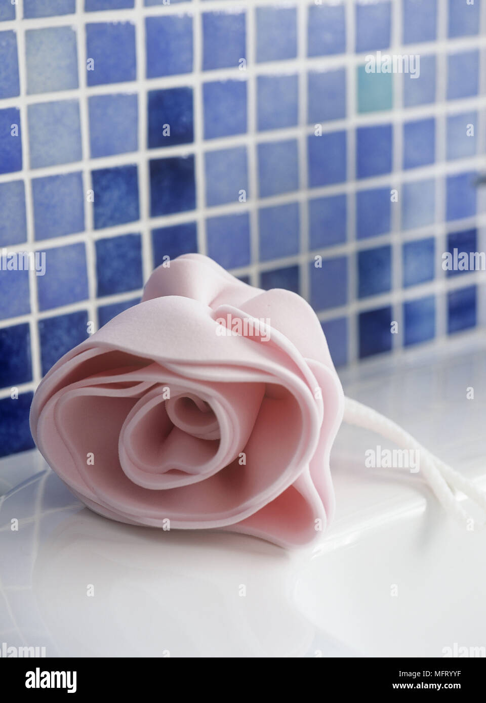 Pink rose shaped shower sponge against blue tiled wall Stock Photo - Alamy