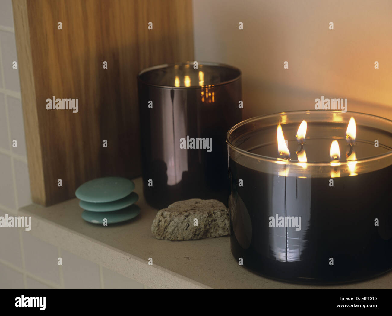 Lit liquid candles in large glass dishes on shelf with coasters and ...