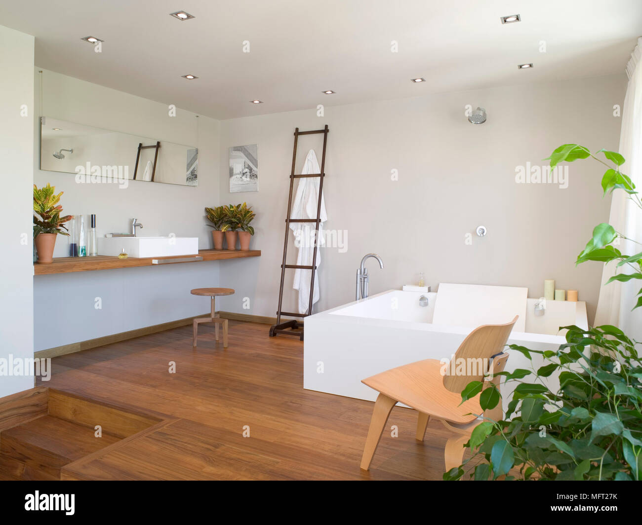 Open plan bathroom with angular bathtub facing mirror and wash basin ...