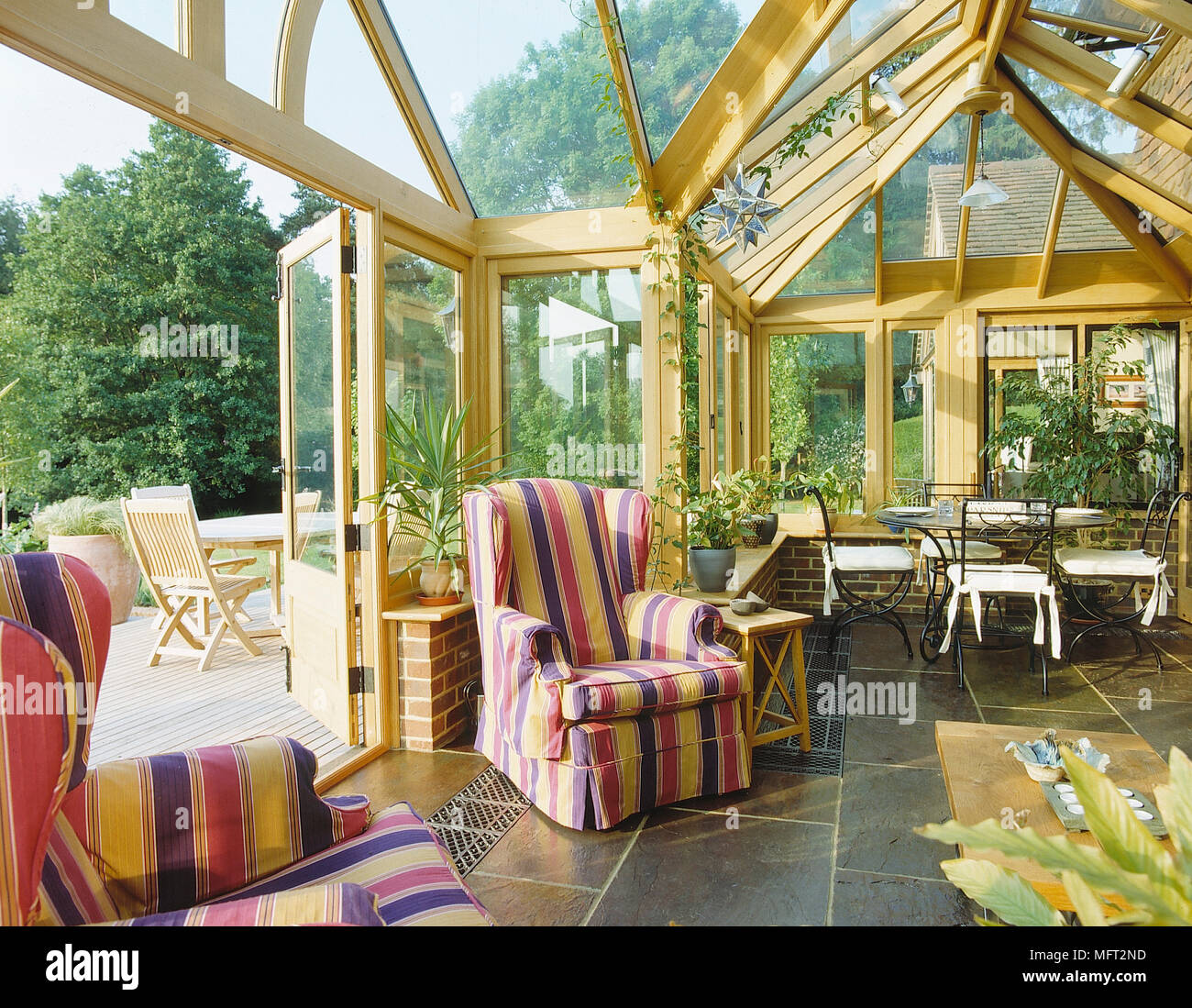 A wooden framed conservatory with slate floor, upholstered armchairs ...