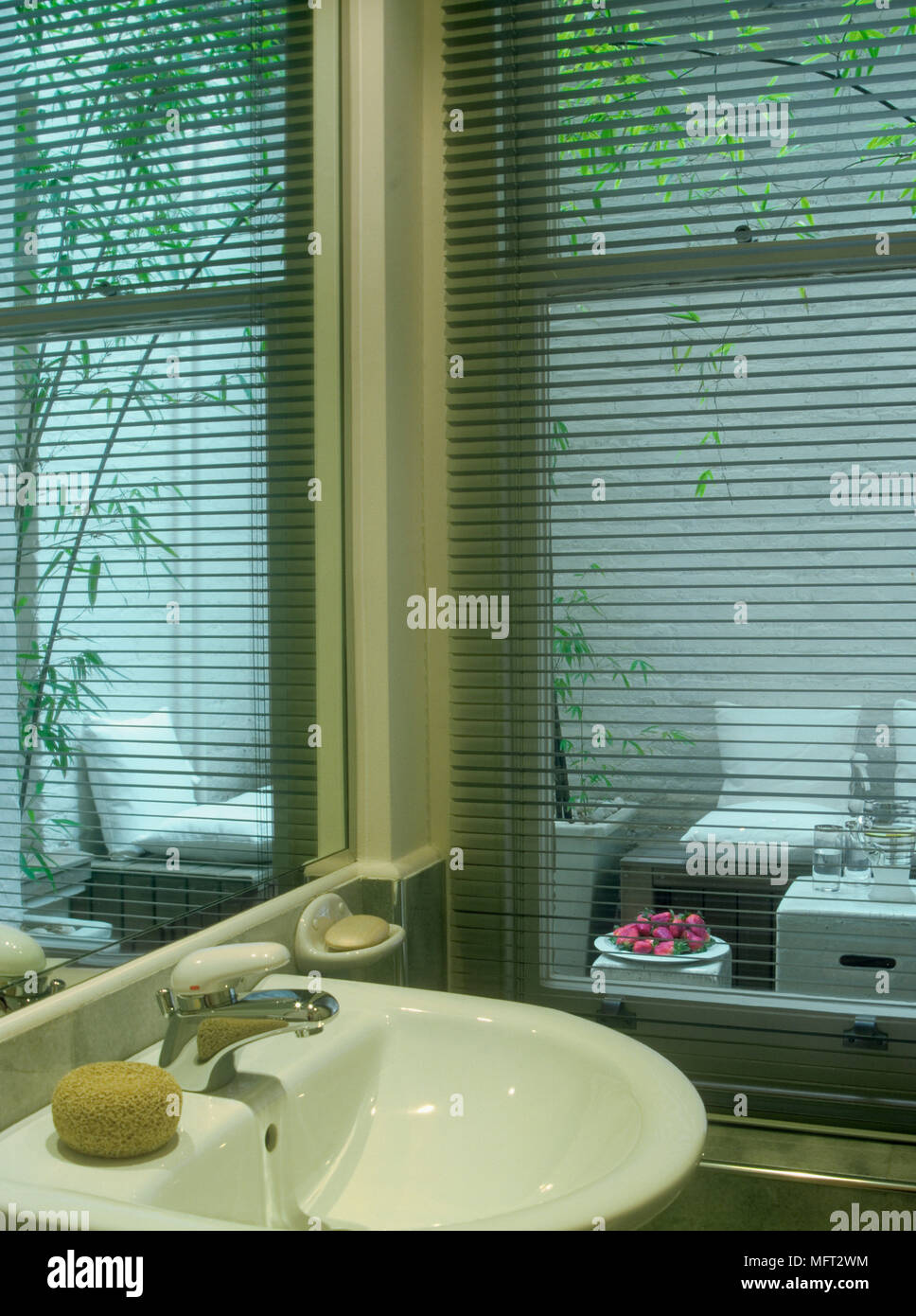 Washbasin beneath mirror window with venetian blind Stock Photo - Alamy
