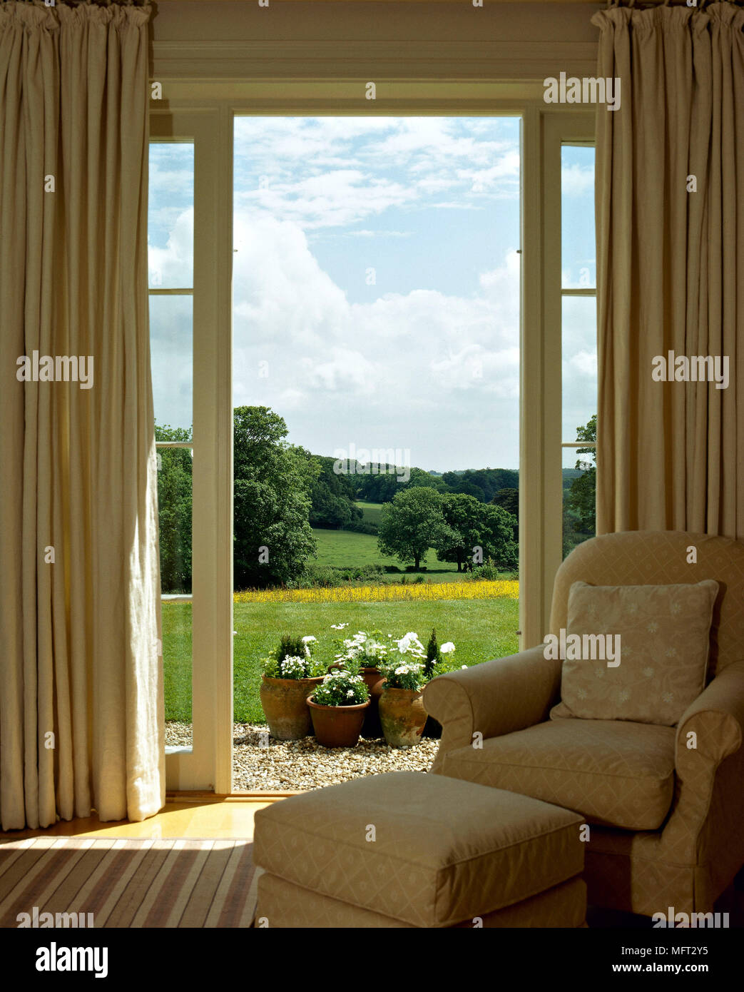 Traditional upholstered armchair and foot rest open doors Interiors ...