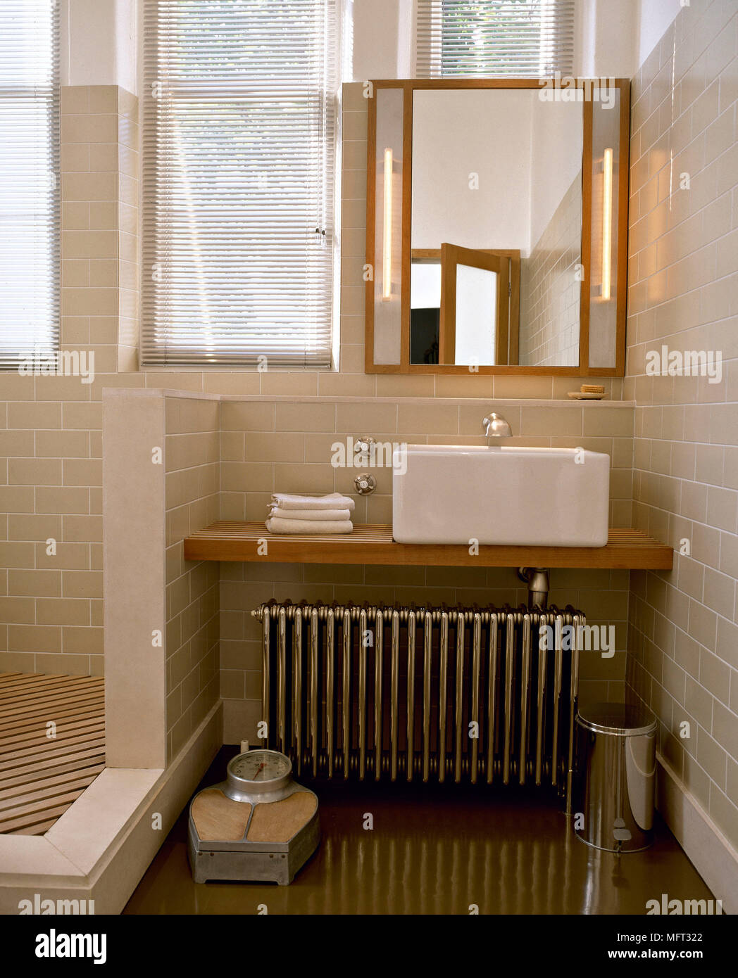 Square washbasin on wooden shelf above radiator next to shower area in ...