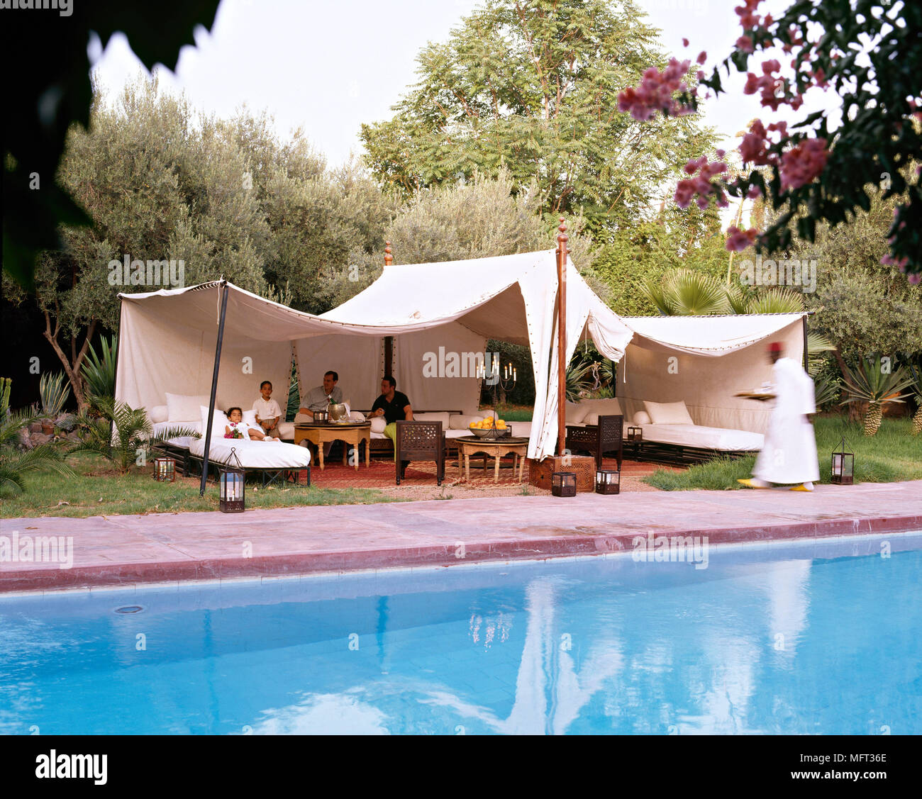 Guests under marquee by outdoor swimming pool hi-res stock photography ...