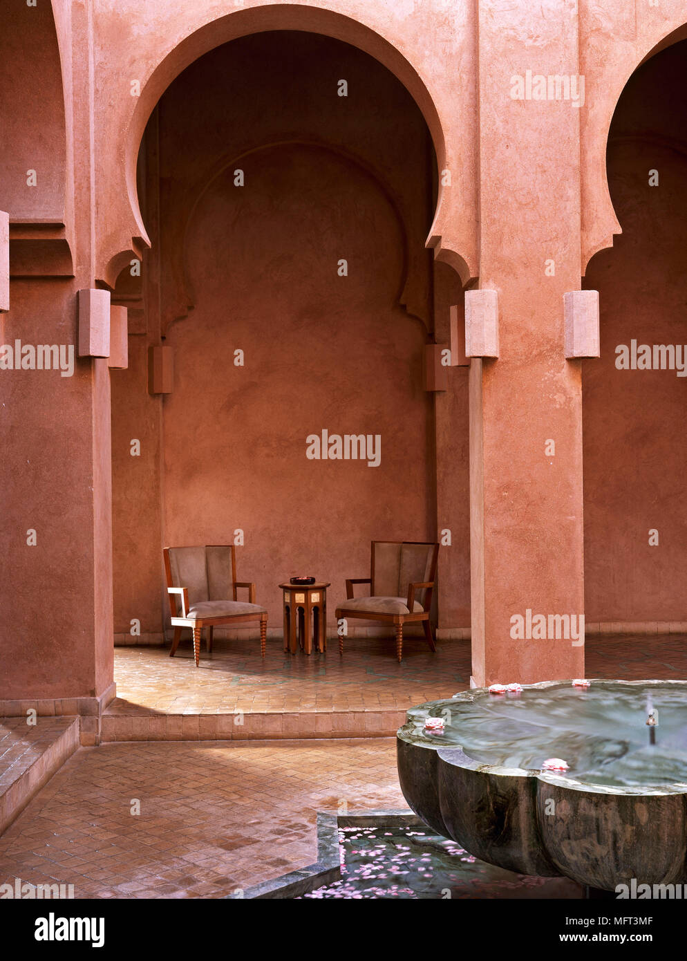 Courtyard Moroccan house terracotta walls pillars armchairs table ...