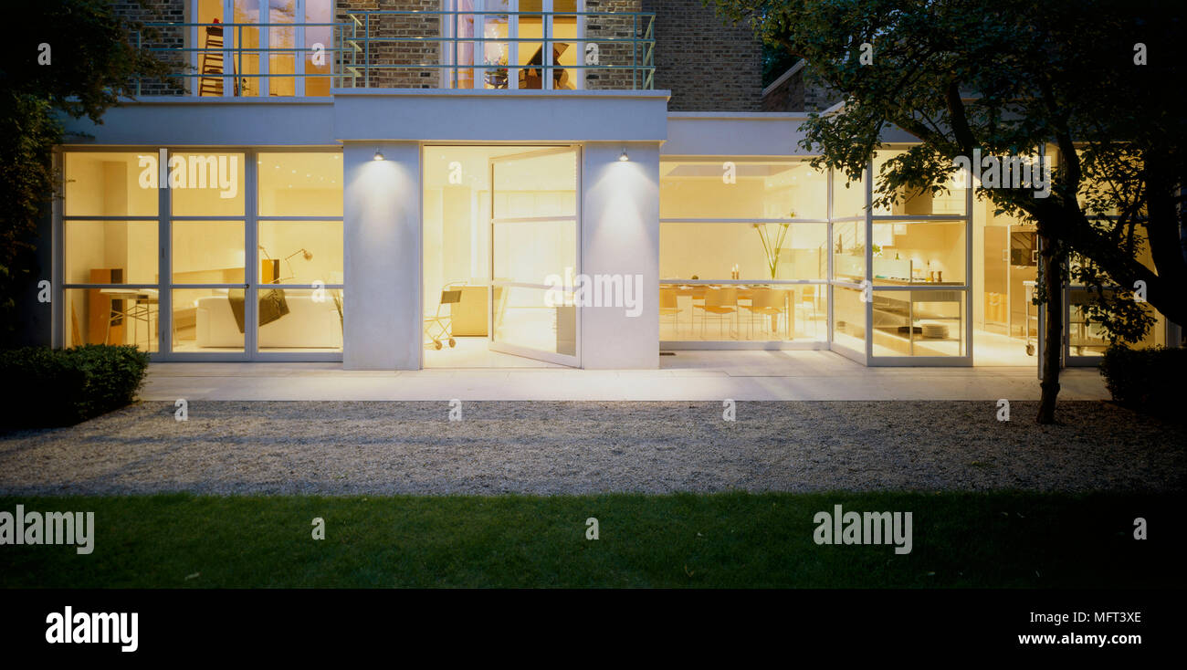 A night shot of the exterior of the rear of a modern house with door ...