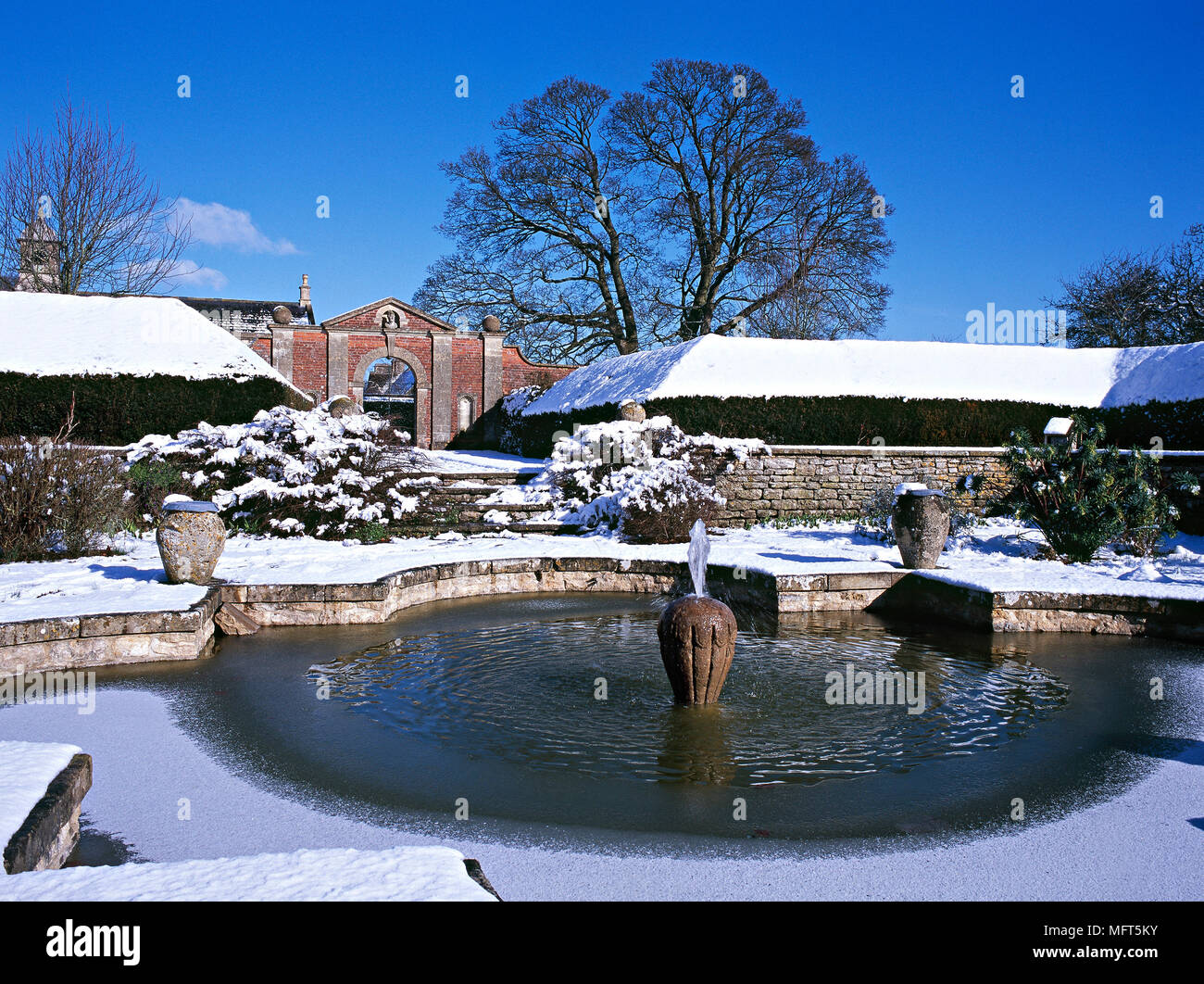 Pond with water feature in a snow covered winter garden Stock Photo - Alamy