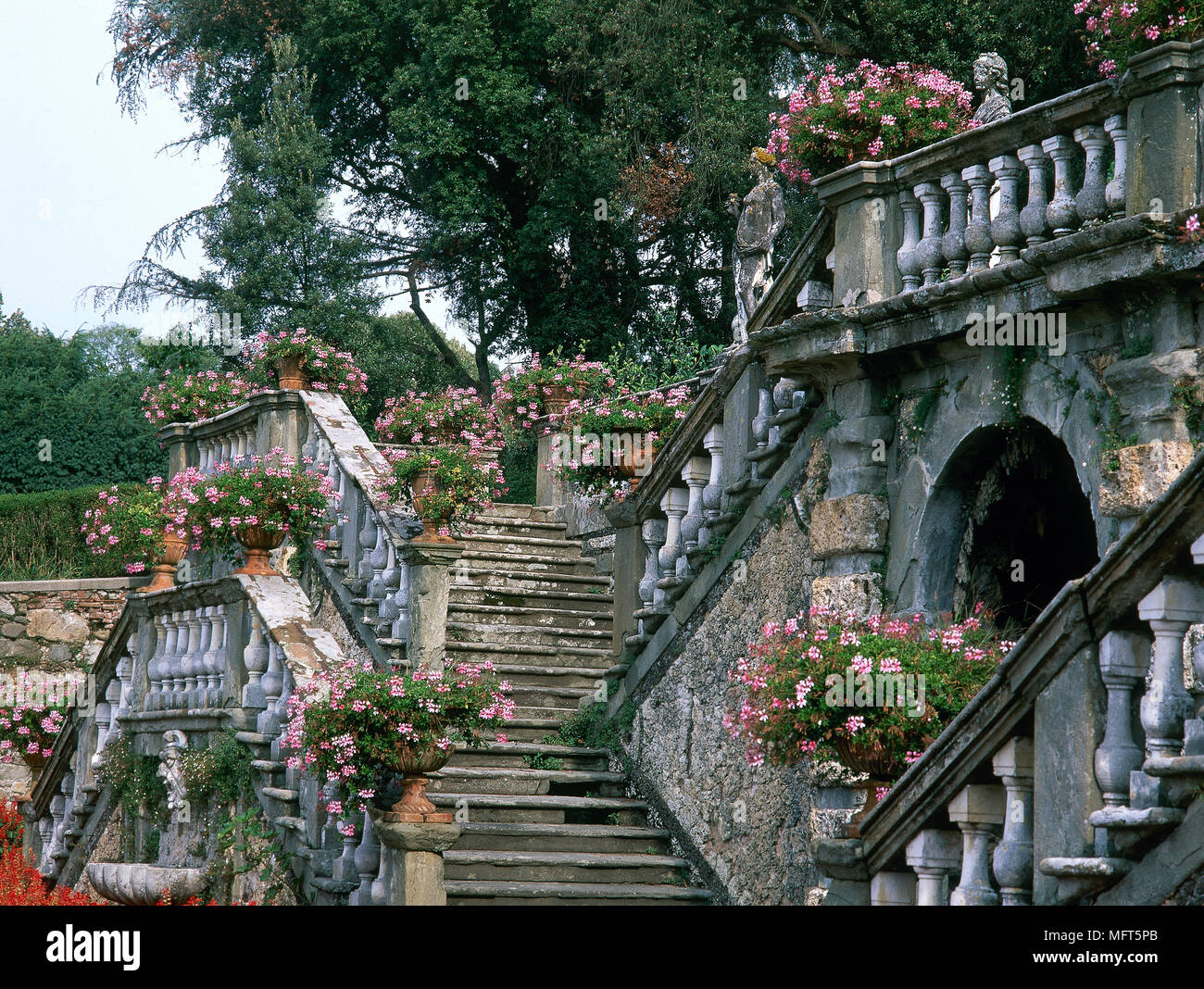 A Italianate garden with stone steps, statues, fountain and pot plants ...
