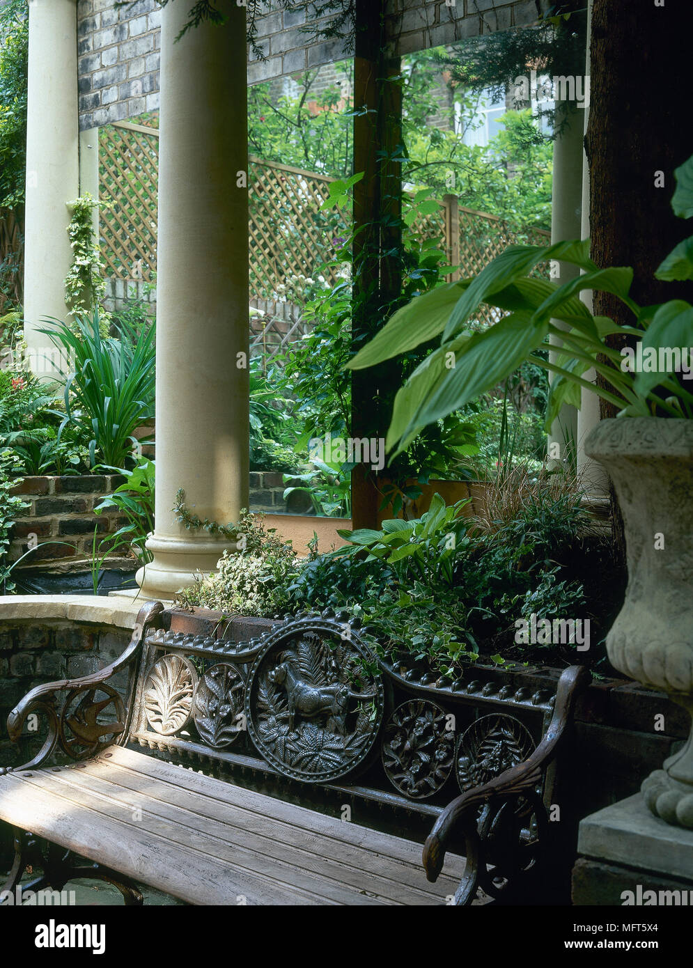 A detail of a courtyard, town garden, bench seat and classical columns ...