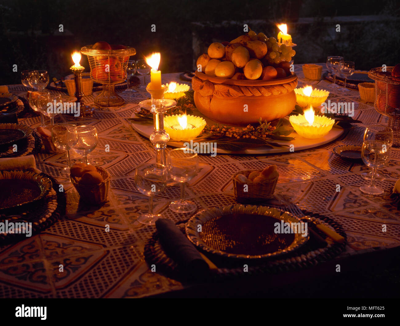 An outdoor table setting at night with lit candles Stock Photo - Alamy