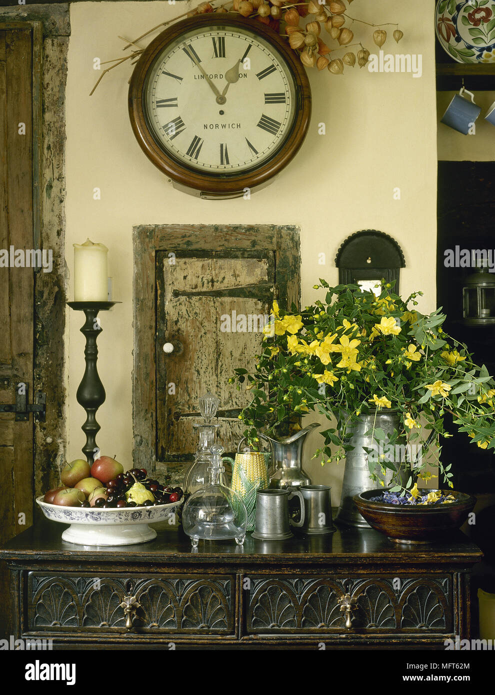 Arrangement of yellow flowers on a carved oak sideboard beneath a ...