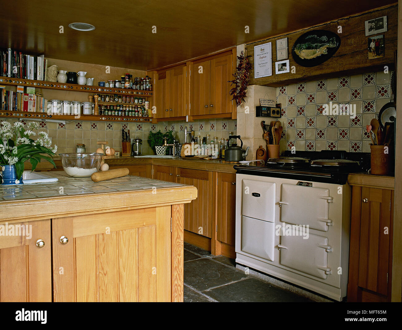 Range oven set in tiled recess in between wooden fitted kitchen units ...