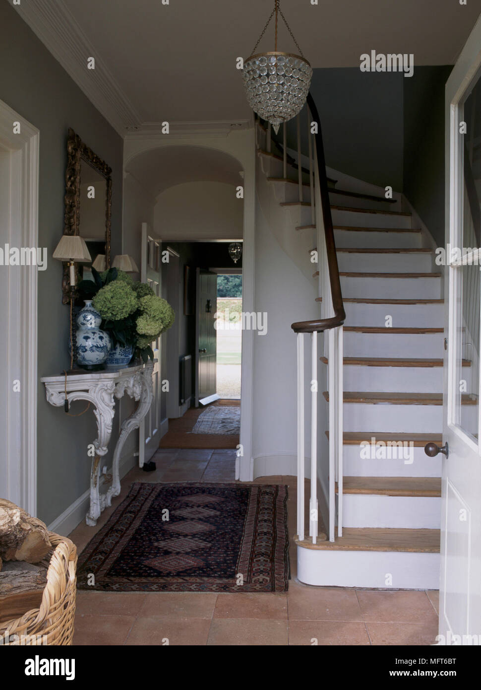 A traditional entrance hall with half glazed door open, staircase ...