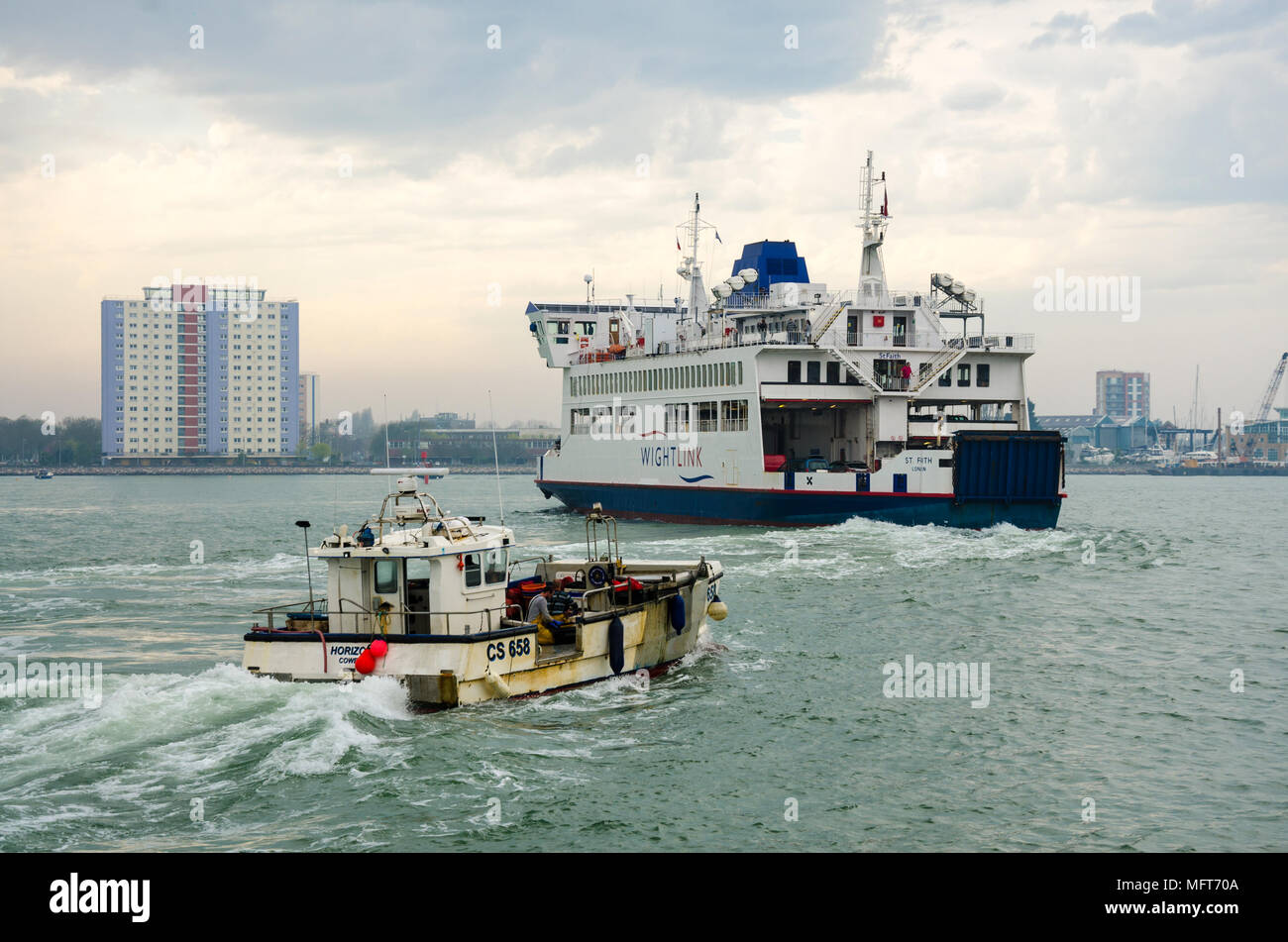A fishing trawler follows a Wight Link car ferry out of Portsmouth ...
