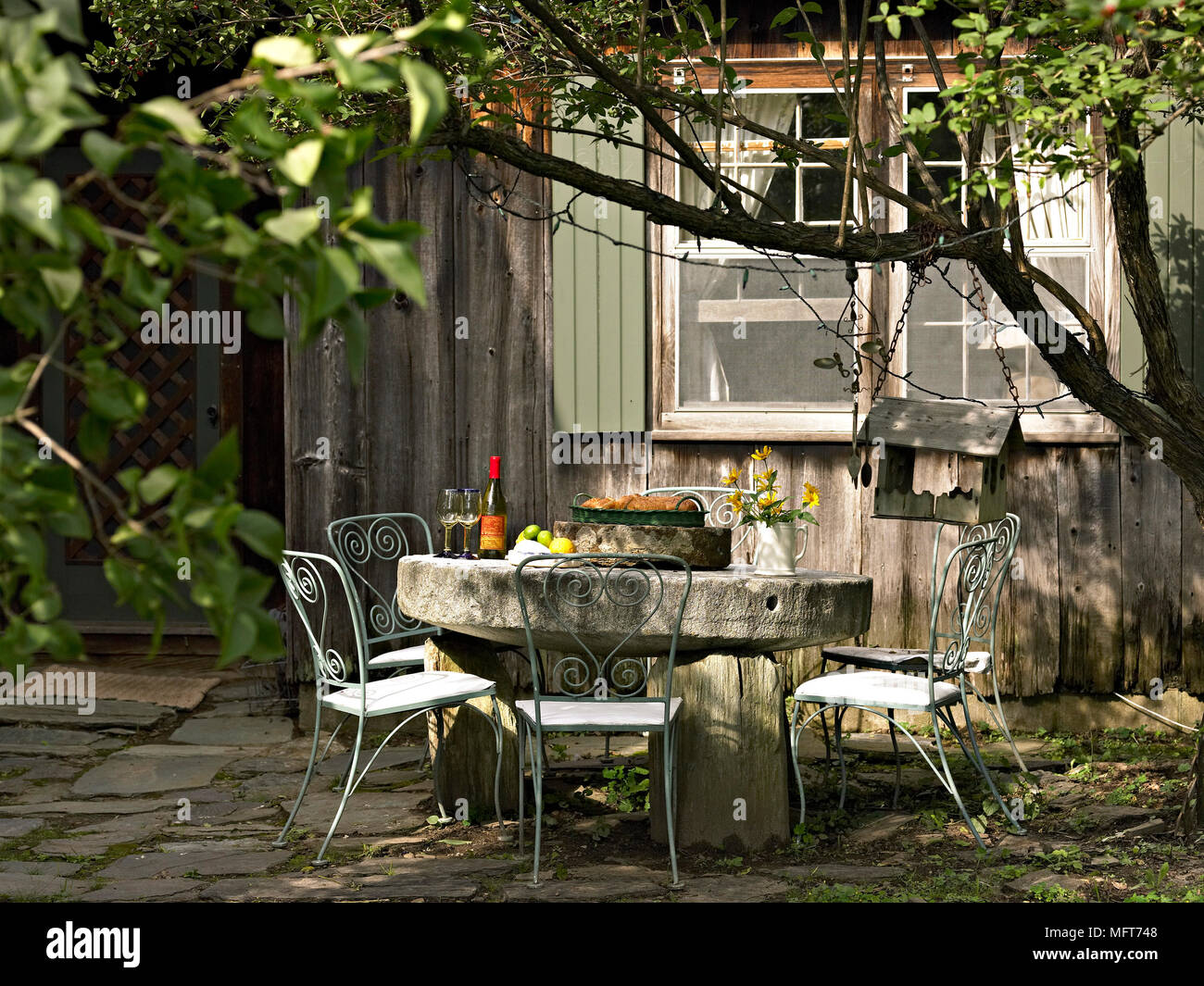 Shady patio area with table and wrought iron chairs Stock Photo - Alamy