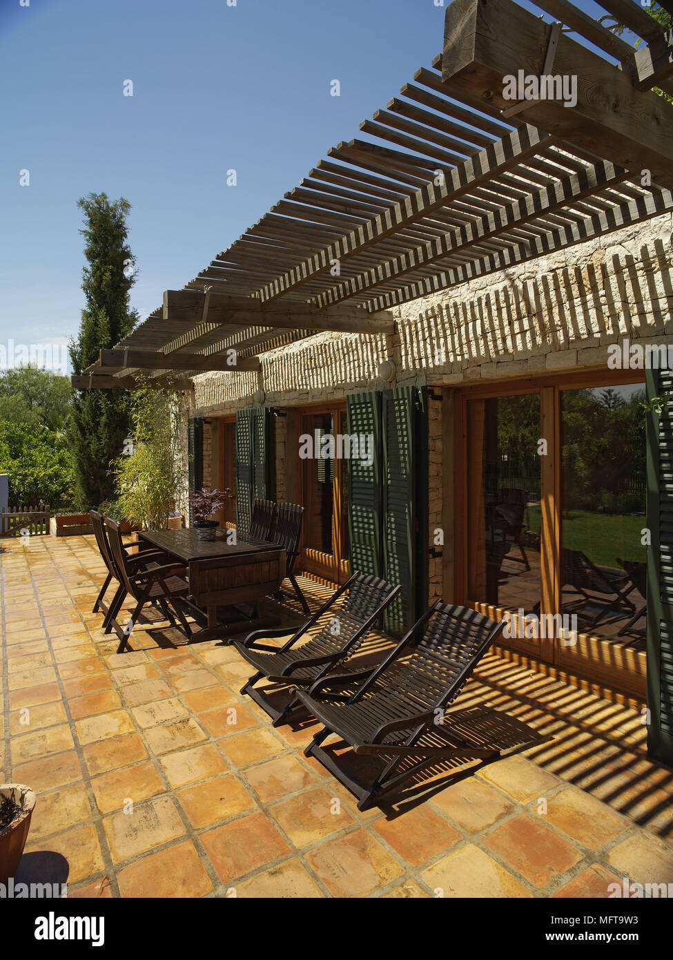 Chairs on paved terrace under the shade of a wooden canopy Stock Photo ...
